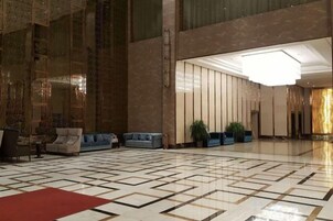 Um hall amplo com piso estampado, área de estar e um grande lustre.