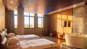 Quarto de hotel com uma cama grande, banheira e vista para a paisagem.