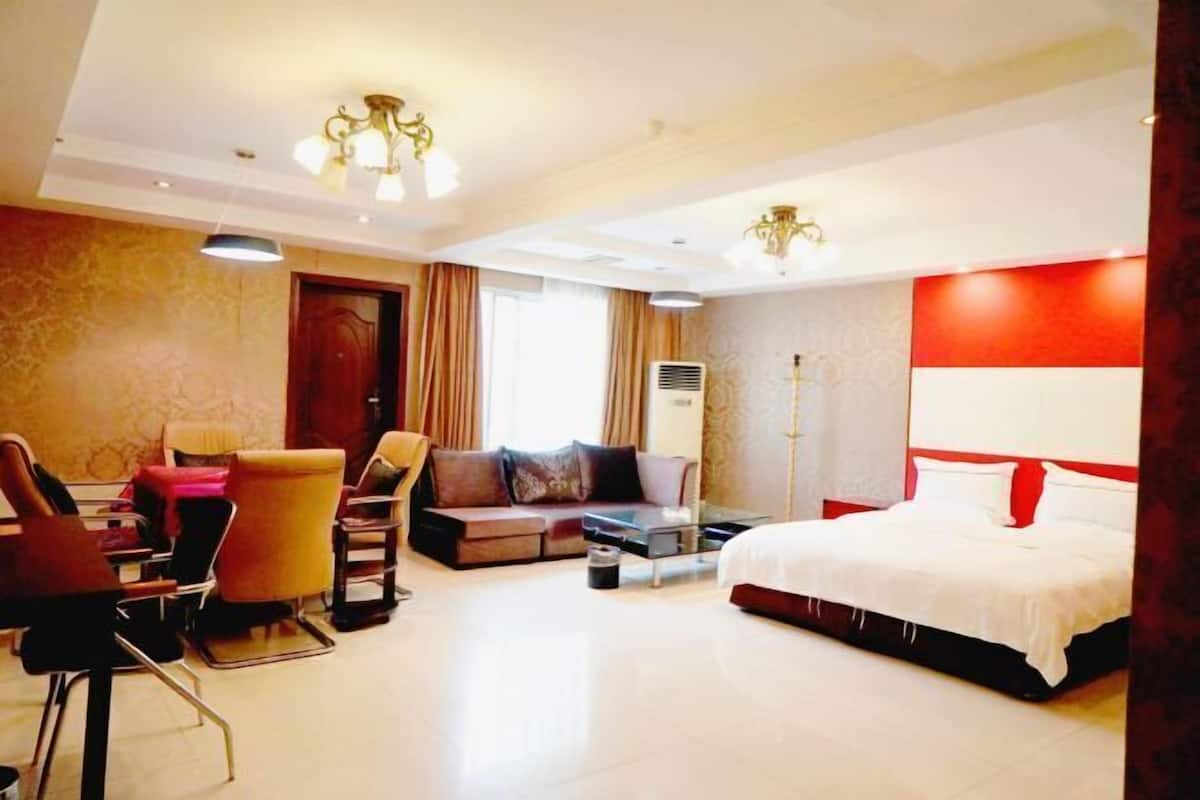 Quarto de hotel com cama, sofá, escrivaninha e cadeira.