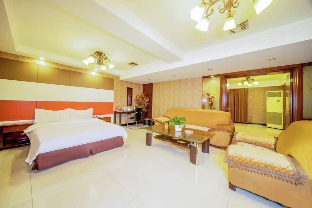 Quarto de hotel com uma cama, um sofá, uma mesa de centro e uma escrivaninha.