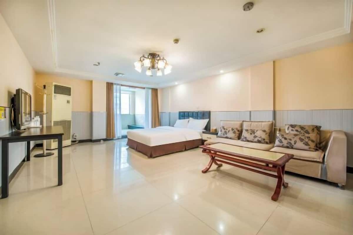 Quarto de hotel com cama, sofá e uma pequena mesa.