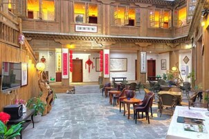 Pátio em estilo tradicional com várias áreas de estar, uma televisão e elementos decorativos.