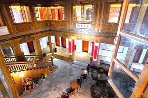 Interior de madeira com vários níveis, um espaço central aberto, áreas de estar e uma escadaria.
