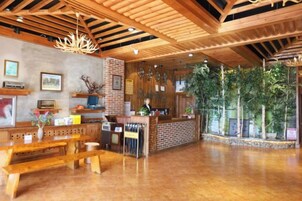Um hall amplo com teto de madeira, balcão de recepção e uma grande planta.