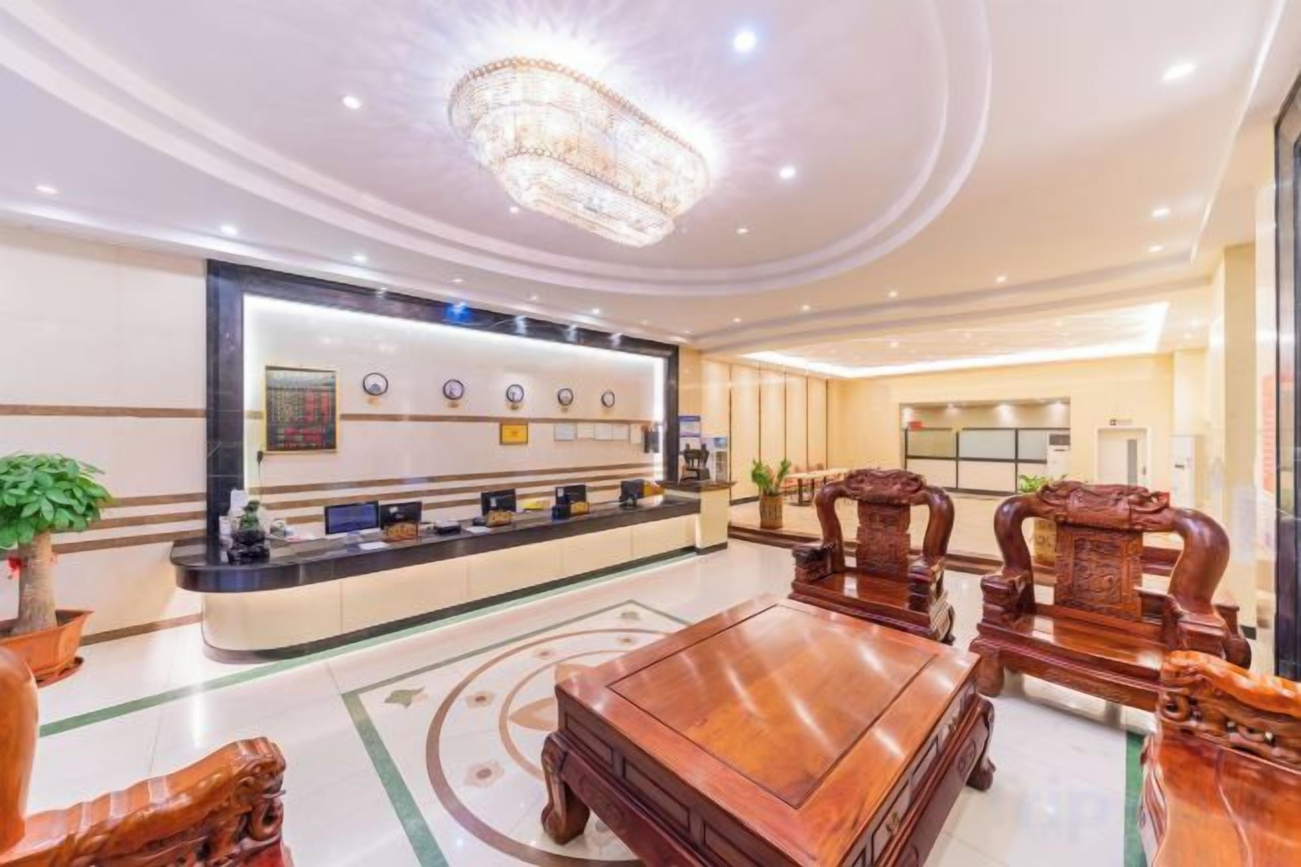 Um saguão de hotel com balcão de recepção, área de estar e um candelabro.