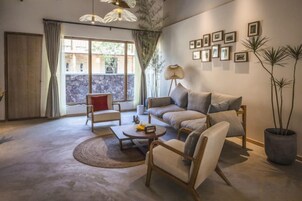 Uma sala de estar com sofá, poltronas, mesinha de centro e um vaso de planta.
