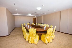 Uma sala de conferências com uma mesa redonda, cadeiras amarelas e carpete bege.