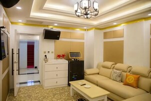 Quarto de hotel com sofá, televisão, escrivaninha e guarda-roupa.
