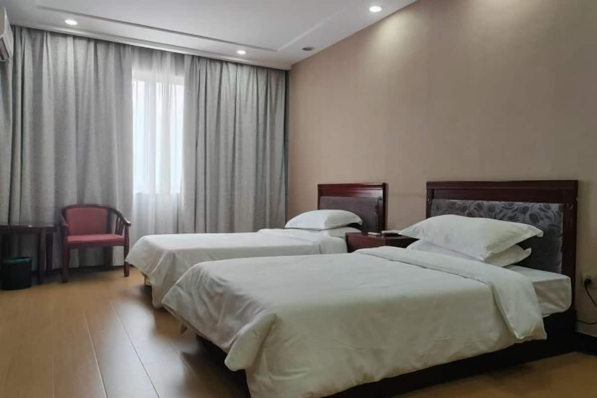 Quarto de hotel com duas camas, uma cadeira e uma mesa.