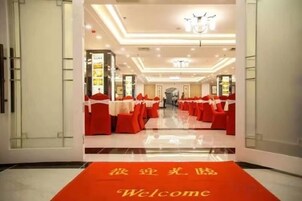 Um hall de hotel com um tapete vermelho que leva a uma área de recepção.