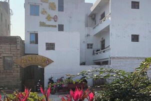 Edifício de vários andares com portão de entrada imponente, varandas e letreiros.