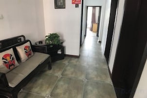 Um corredor com um sofá, uma planta e piso de azulejos.