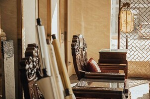 Quarto tradicional com uma cadeira de madeira, uma mesinha e um candeeiro decorativo.