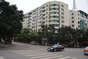 Um edifício com vários andares e design arquitetônico moderno, com entrada destacada e uma estrutura de antena visível.