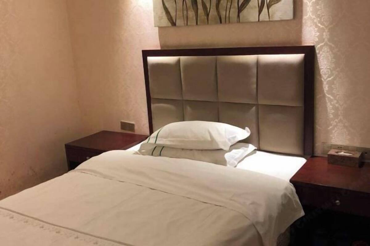 Quarto de hotel com cama, mesa de cabeceira, cabeceira e uma obra de arte pendurada na parede.