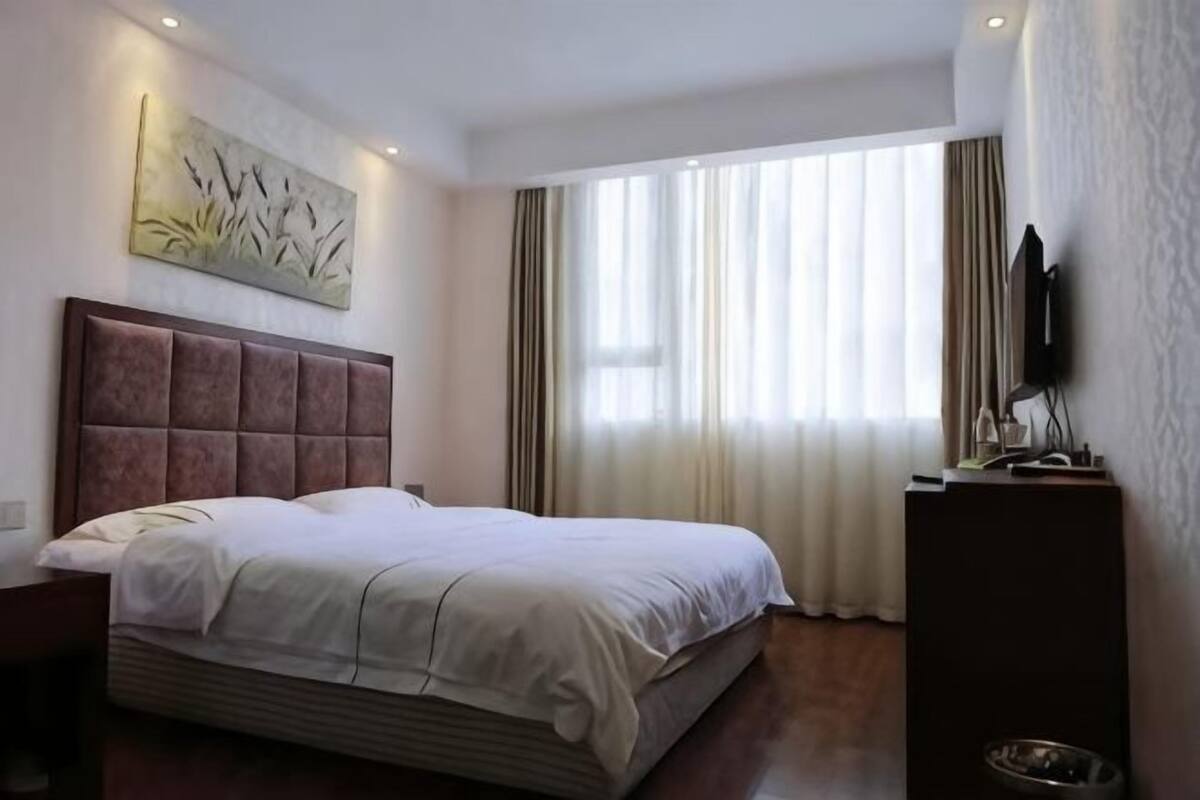 Quarto de hotel com uma cama grande, uma televisão de tela plana e um quadro na parede.