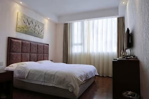 Quarto de hotel com uma cama grande, uma televisão de tela plana e um quadro na parede.