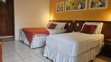 Quarto de hotel com duas camas, uma porta de madeira e obras de arte na parede.