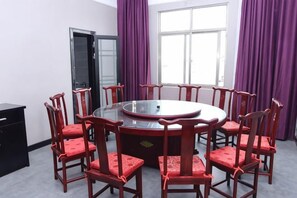 Uma sala de conferências com uma mesa redonda, cadeiras vermelhas e um armário de arquivos preto.