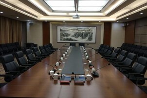 Uma sala de conferências com uma mesa comprida, cadeiras e uma tela de projeção.