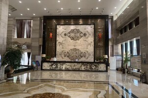Um hall de entrada com uma receção de mármore, uma parede decorativa grande e um chão estampado.
