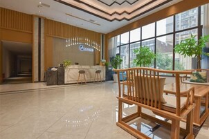 Um hall de hotel com balcão de recepção, área de estar e grandes janelas.