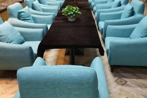 Quarto com uma mesa comprida e várias poltronas azul claro dispostas ao redor.