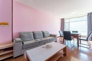 Uma sala de estar moderna com um sofá cinzento, uma mesa de centro de madeira e um espaço de jantar com mesa e cadeiras.