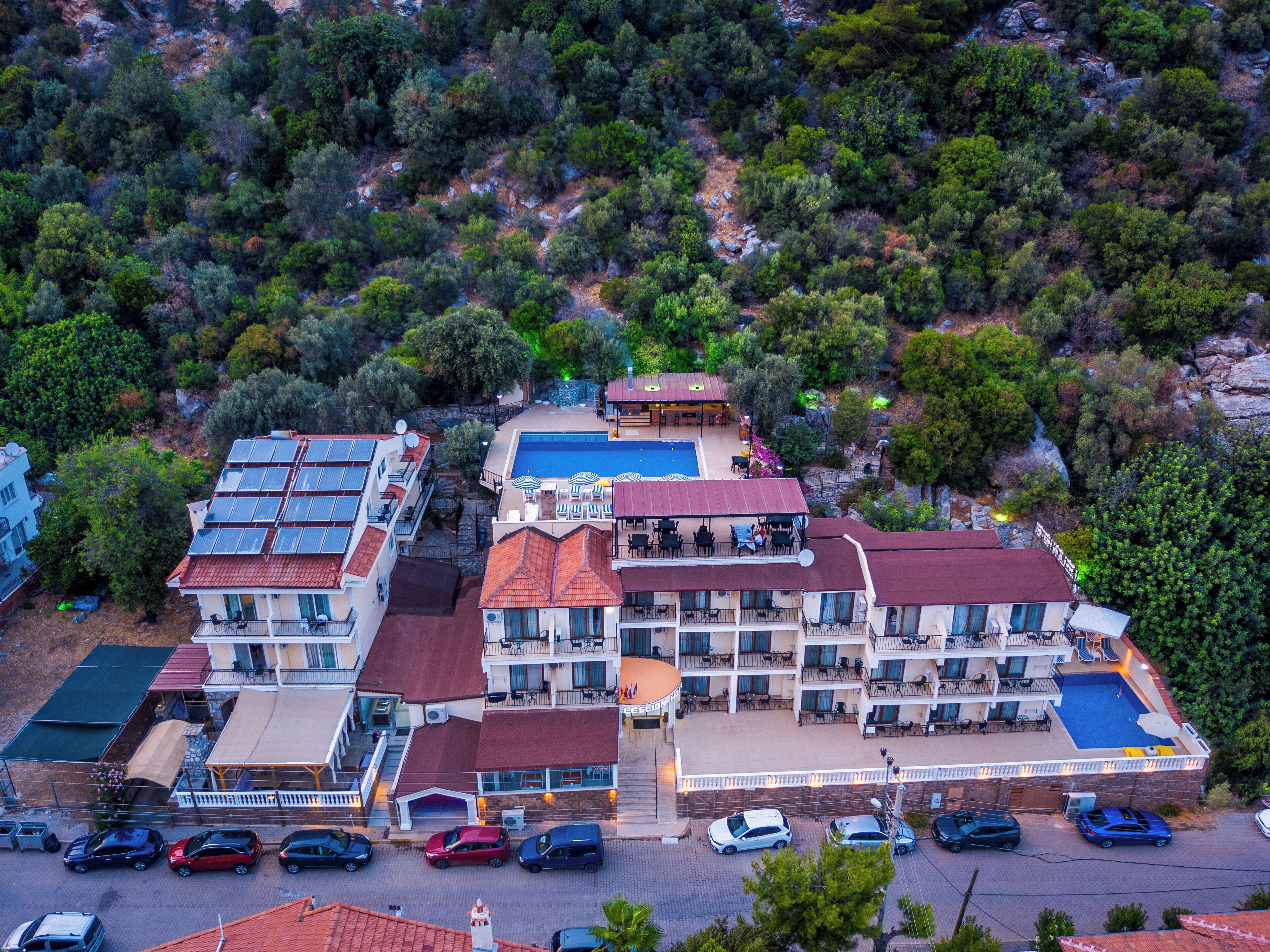 Um hotel com vários andares, piscina no terraço, diversas varandas e área de estacionamento.