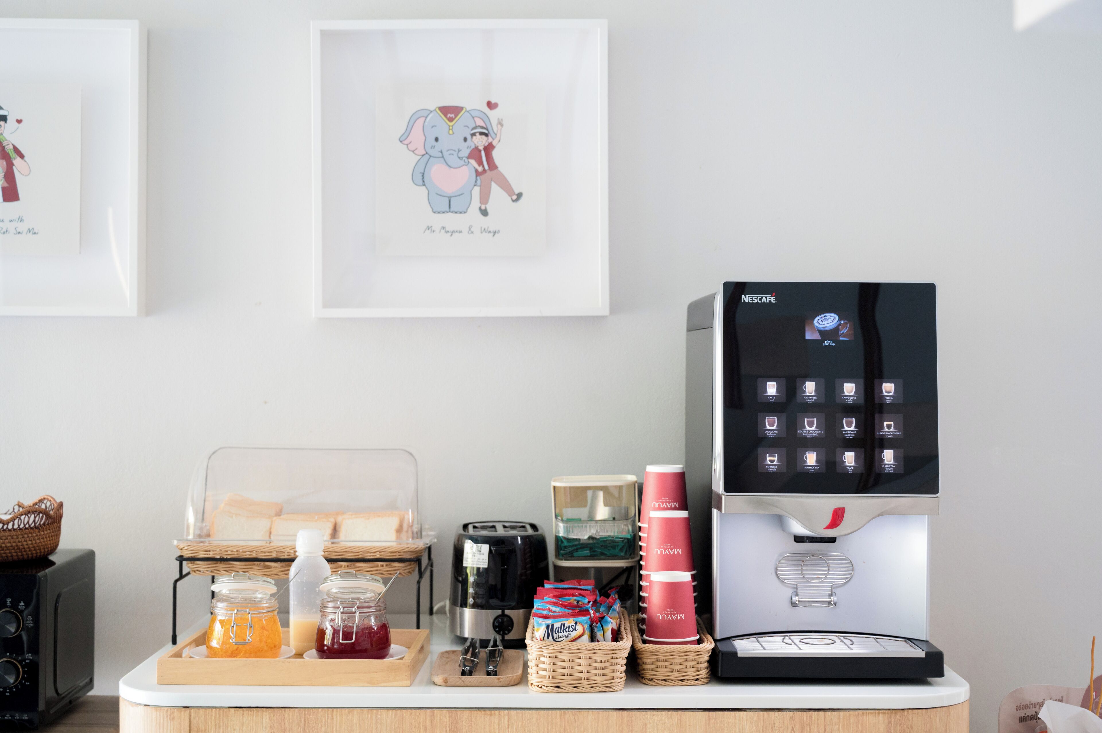 Uma mesa de pequeno-almoço com máquina de café, torradeira e diversas opções de comida.