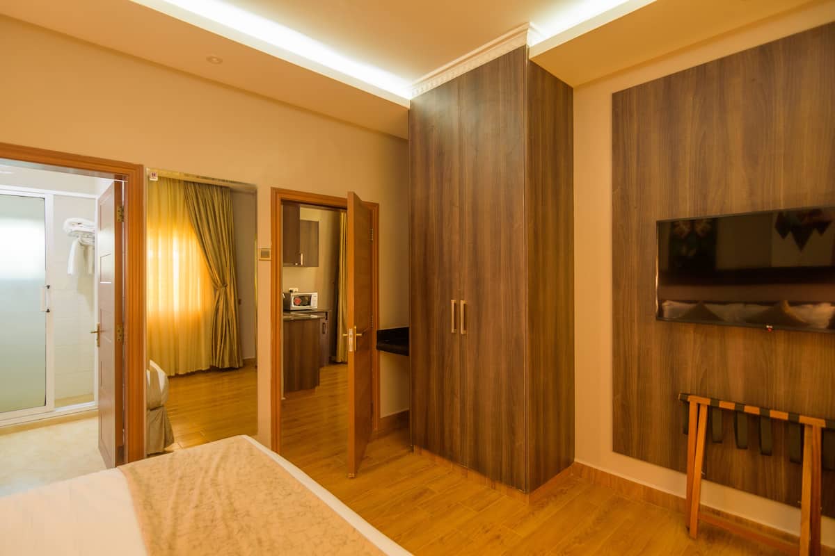 Quarto de hotel com cama, guarda-roupa, televisão e uma pequena mesa.