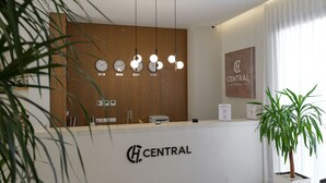 Uma mesa de recepção com painel de madeira e uma placa com o texto "CENTRAL HOTEL".