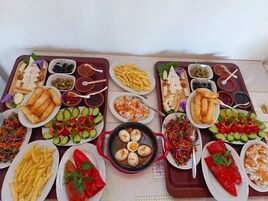 Uma mesa com diversos pratos, incluindo comidas fritas, saladas e uma panela de ovos.
