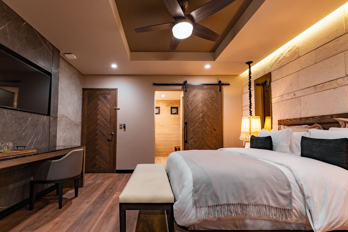 Quarto de hotel moderno com uma cama grande, uma escrivaninha e um banco.