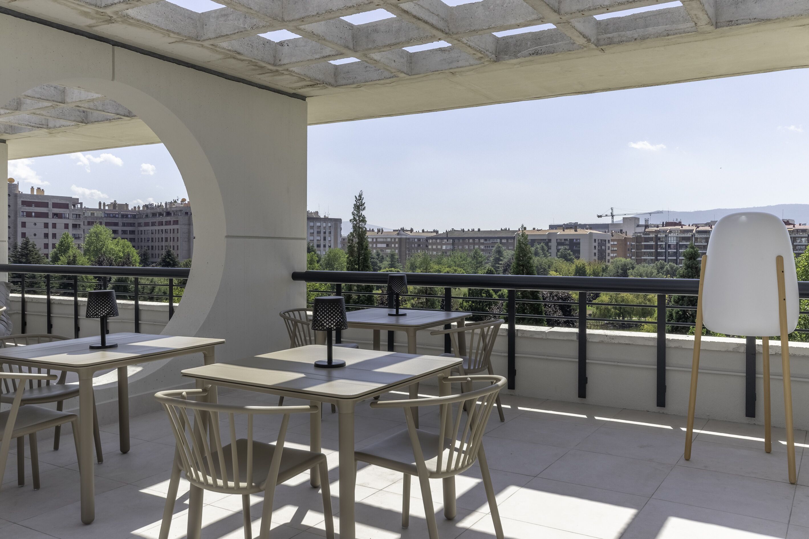 Terraço no telhado com mesas e cadeiras, proporcionando vista dos edifícios ao redor.