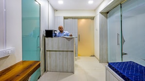 Quarto de hotel compacto com escrivaninha, cama e divisória de vidro.