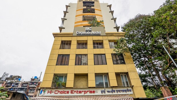 Um edifício de vários andares com uma placa indicando BKC Corporate Hostel e uma fachada para Hi-Choice Enterprise.