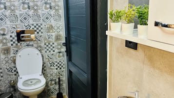 Casa de banho com sanita, lavatório e porta preta.