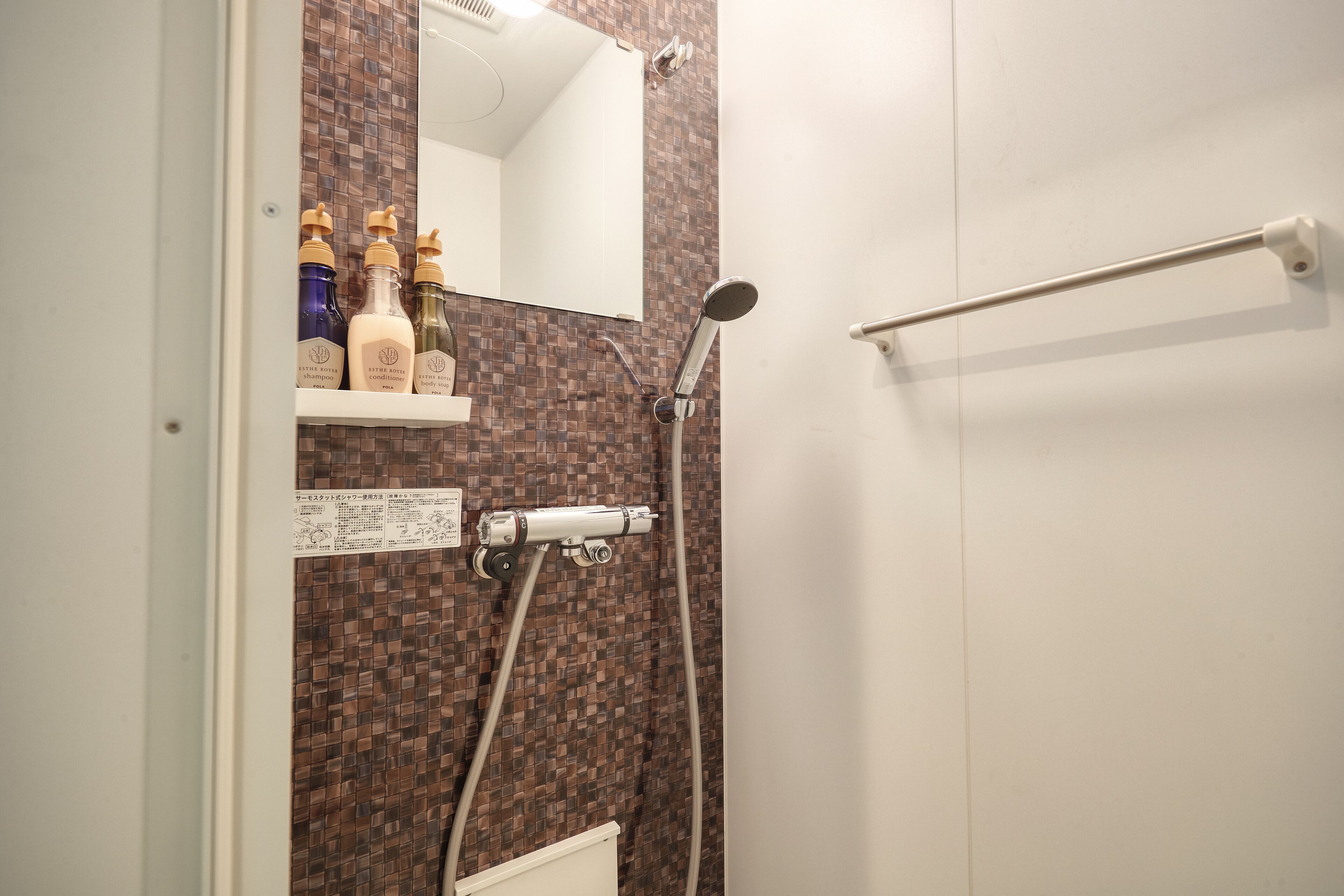 Casa de banho com chuveiro, um porta-toalhas e um armário com produtos de higiene.