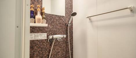 Casa de banho com chuveiro, um porta-toalhas e um armário com produtos de higiene.