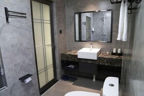 Casa de banho moderna com lavatório de mármore, sanita e chuveiro.