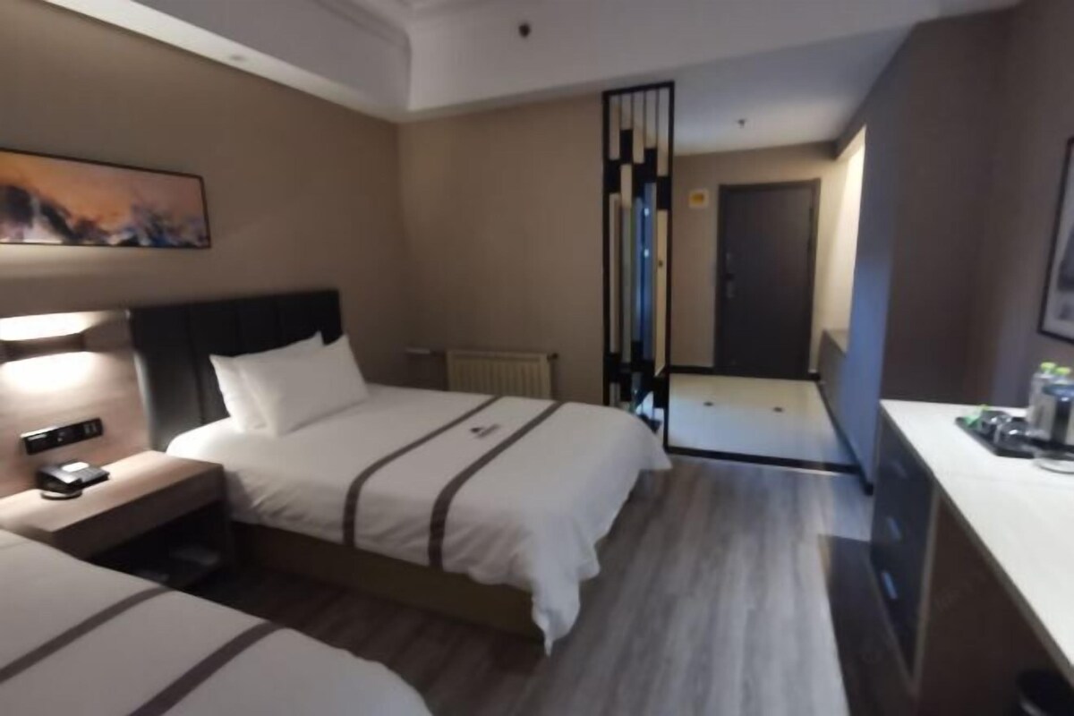 Quarto de hotel com cama, mesa de cabeceira e escrivaninha com cadeira.