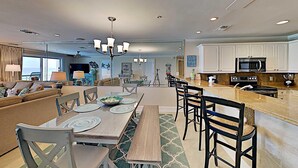 Uma sala moderna com área de jantar, cozinha e vista para o oceano.