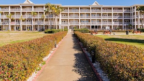Um hotel com vários andares e uma galeria central ladeada por sebes bem cuidadas.