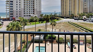 Um hotel moderno com várias varandas, piscina e vista para a praia e oceano.
