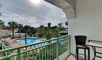 Uma varanda com vista para uma piscina, espreguiçadeiras e uma mesa.