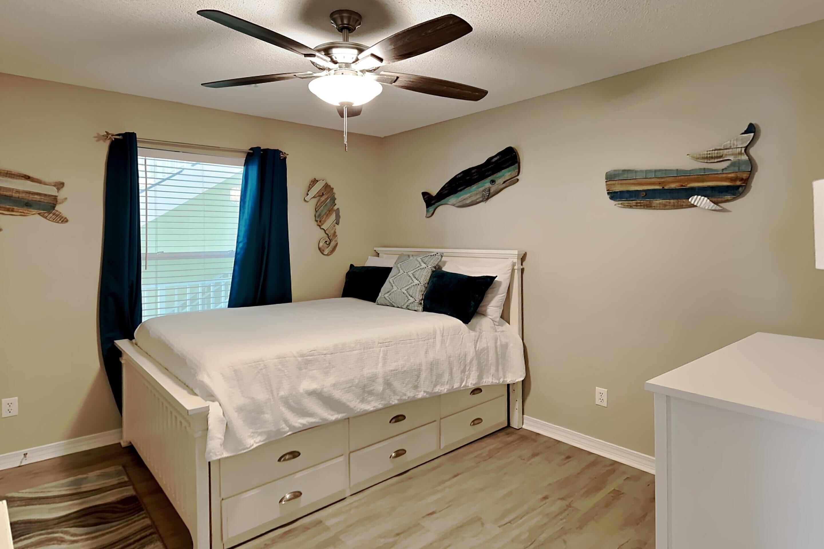 Quarto com cama, ventilador de teto e obras de arte nas paredes.