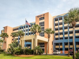 Hotel com design moderno, exibindo uma bandeira americana em destaque, vários andares e área de estacionamento.