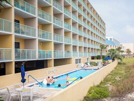 Um hotel com várias varandas, piscina e área de estar ao ar livre.