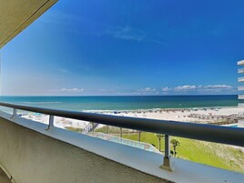 Uma varanda com vista para a praia e o oceano.
